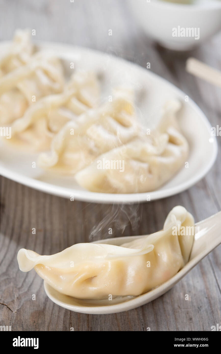 Fresh dumpling on spoon with hot steams. Chinese food on old wooden ...