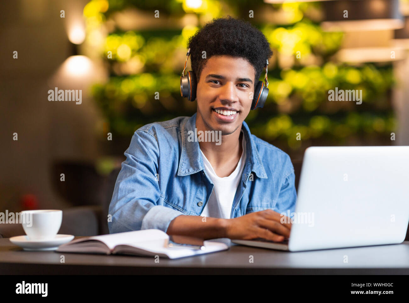 Cheerful teen guy with headset working with laptop Stock Photo - Alamy