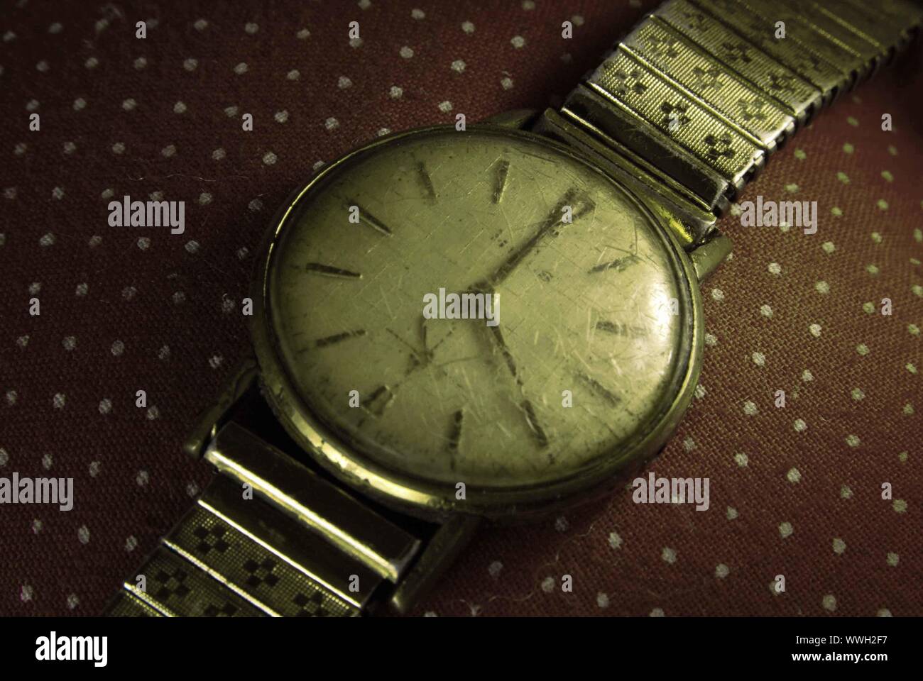 Retro golden wristwatch close up on old fashioned cloth background ...