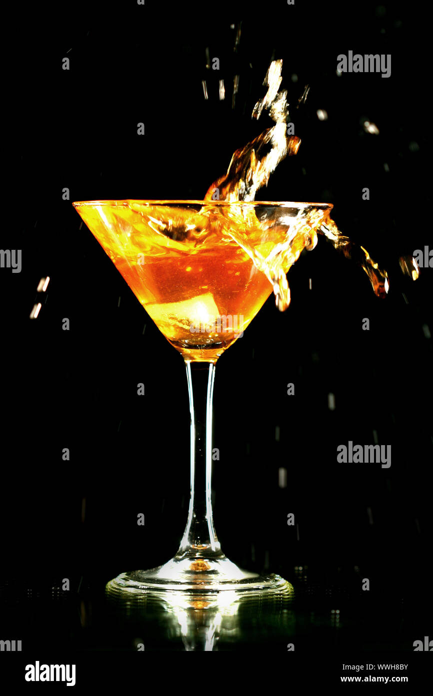 alcohol splash in martini glass on black background Stock Photo - Alamy