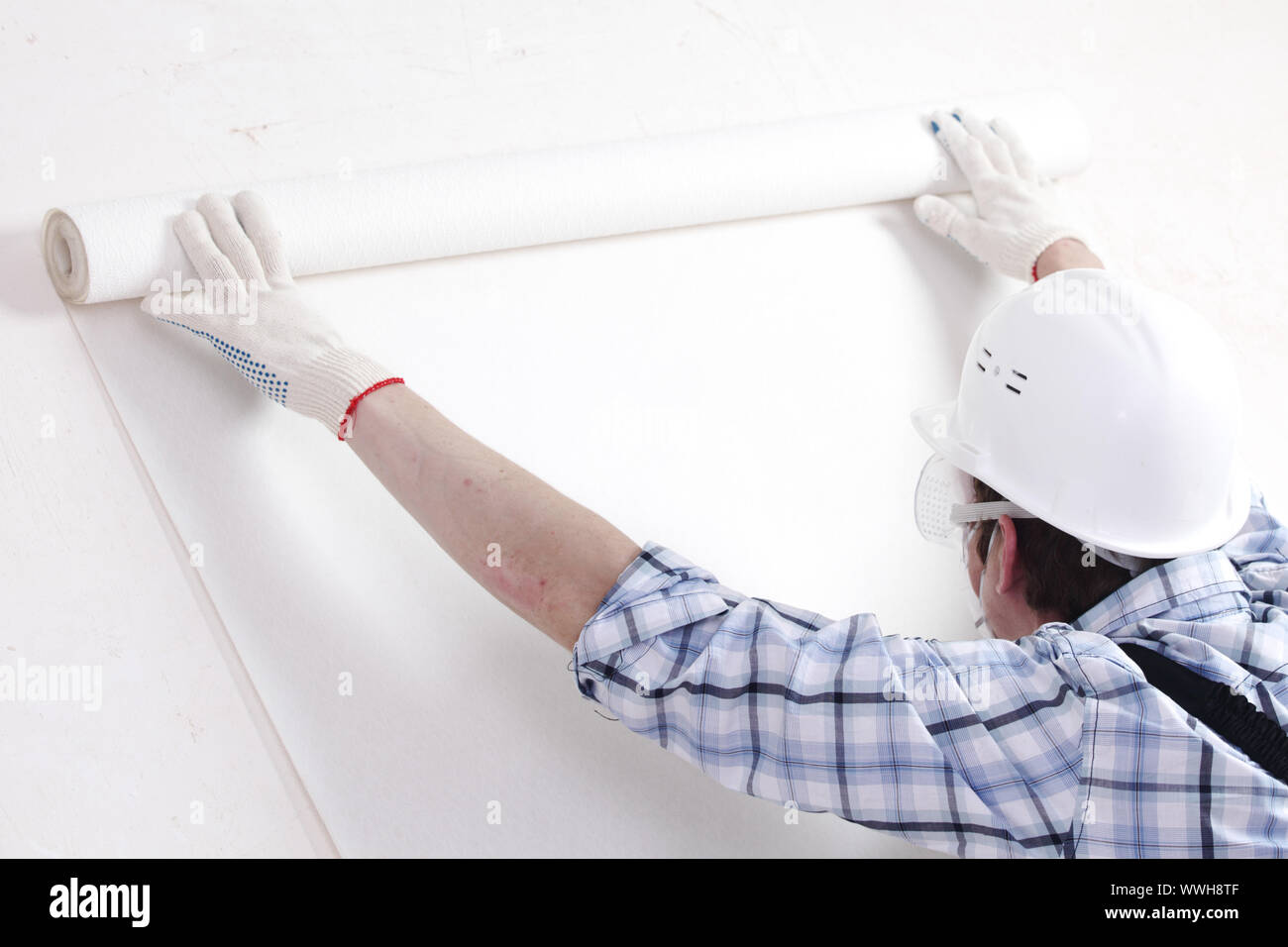 worker attaching wallpaper to wall Stock Photo - Alamy