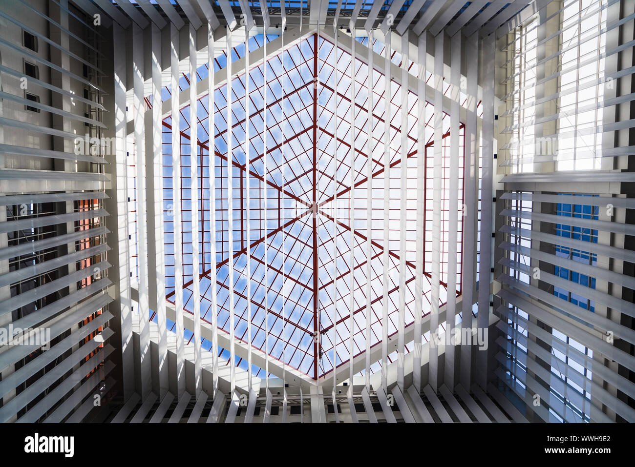 Looking up at the skylight glass roof of an atrium, with geometric structure in modern ...