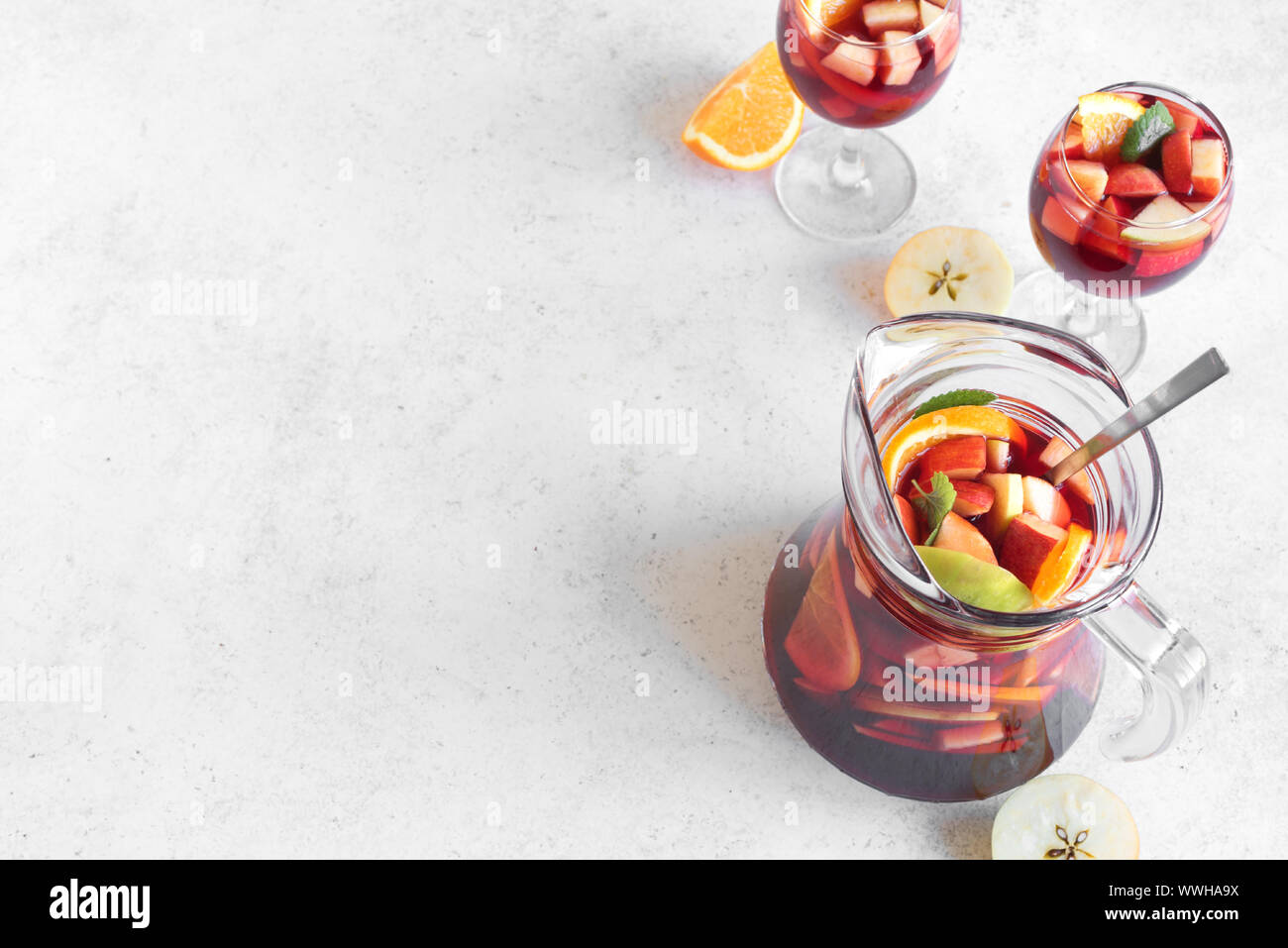 Red wine sangria or punch with fruits and ice in glasses and pitcher ...