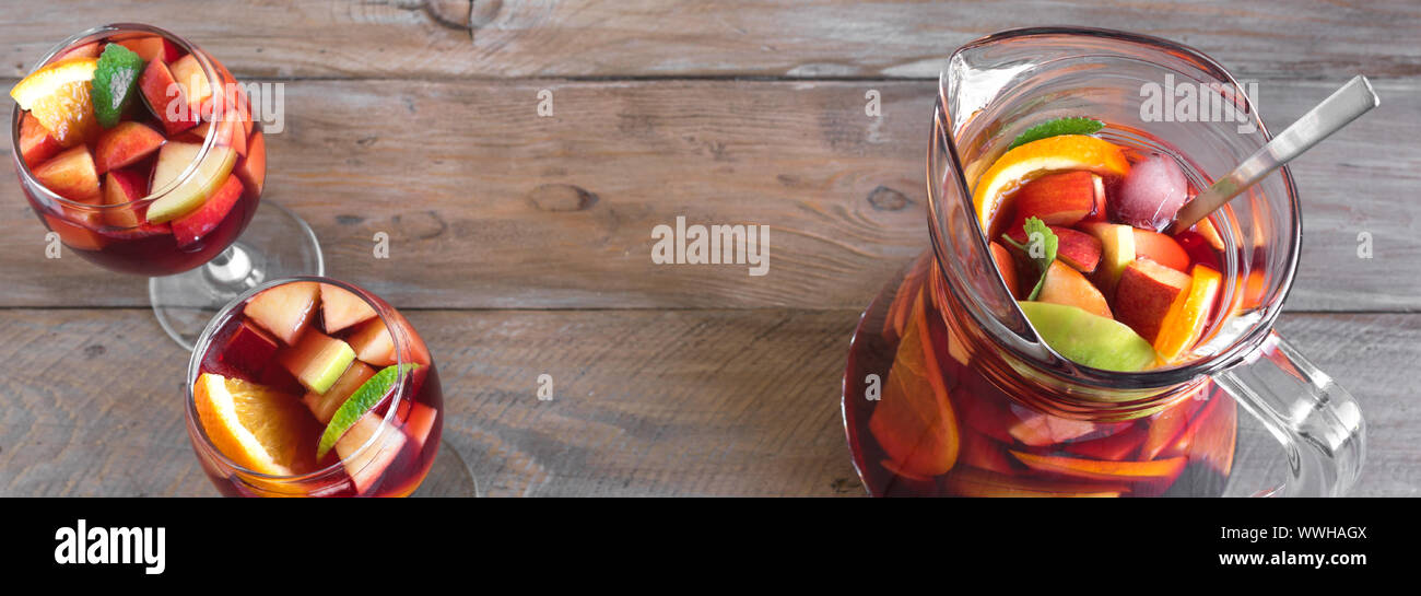 Red wine sangria or punch with fruits and ice in pitcher and glasses ...