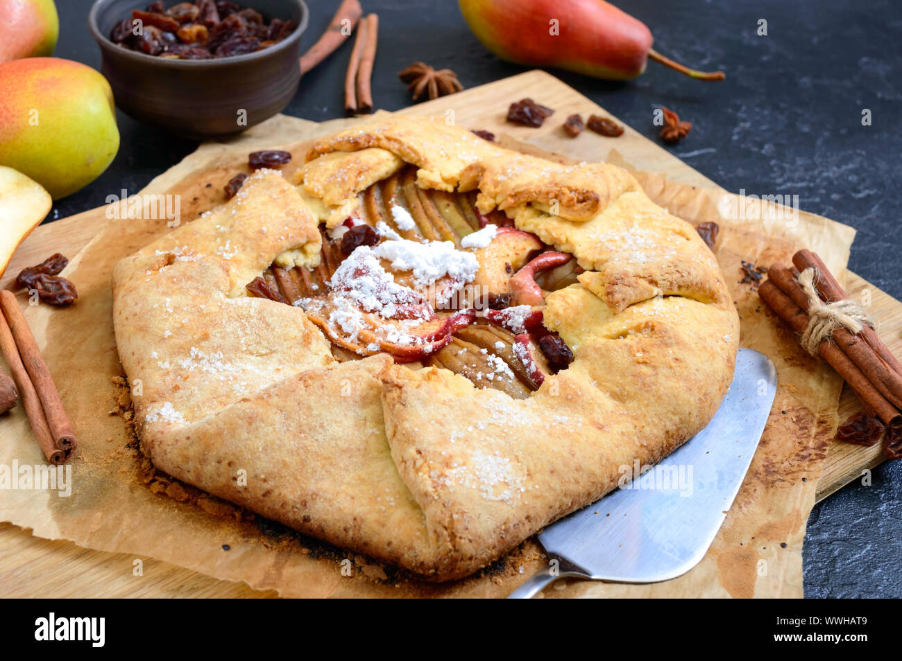 Caramelized pear pie with cinnamon and raisins on a black background ...