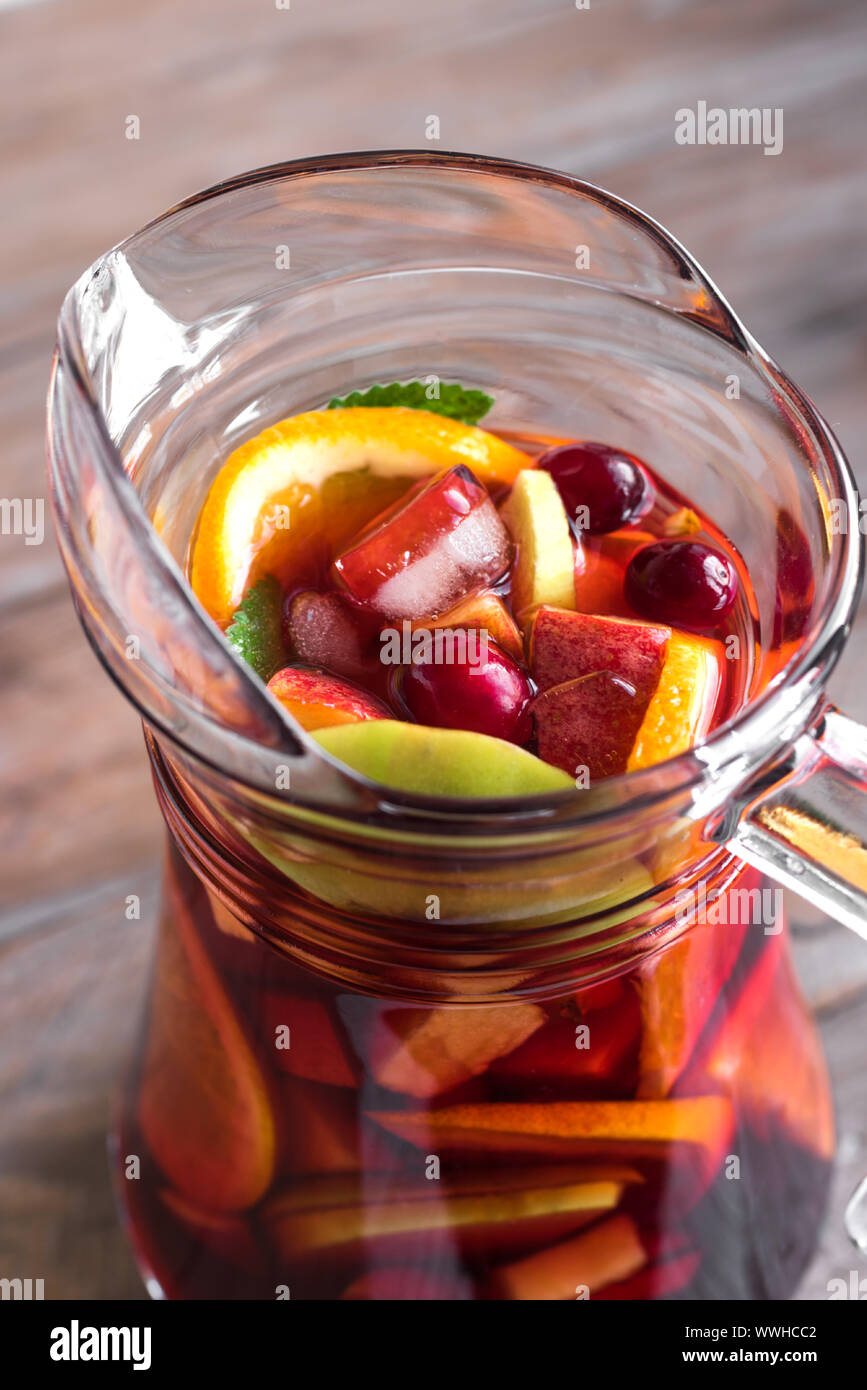 Red wine sangria or punch with fruits and ice in pitcher. Homemade ...