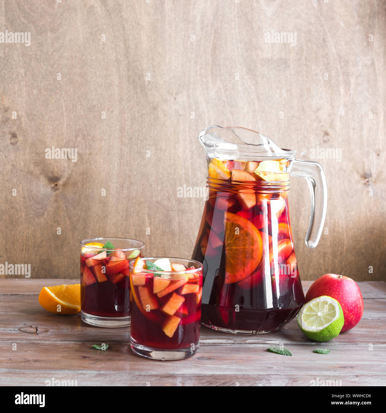 Red wine sangria or punch with fruits and ice in glasses and pincher ...
