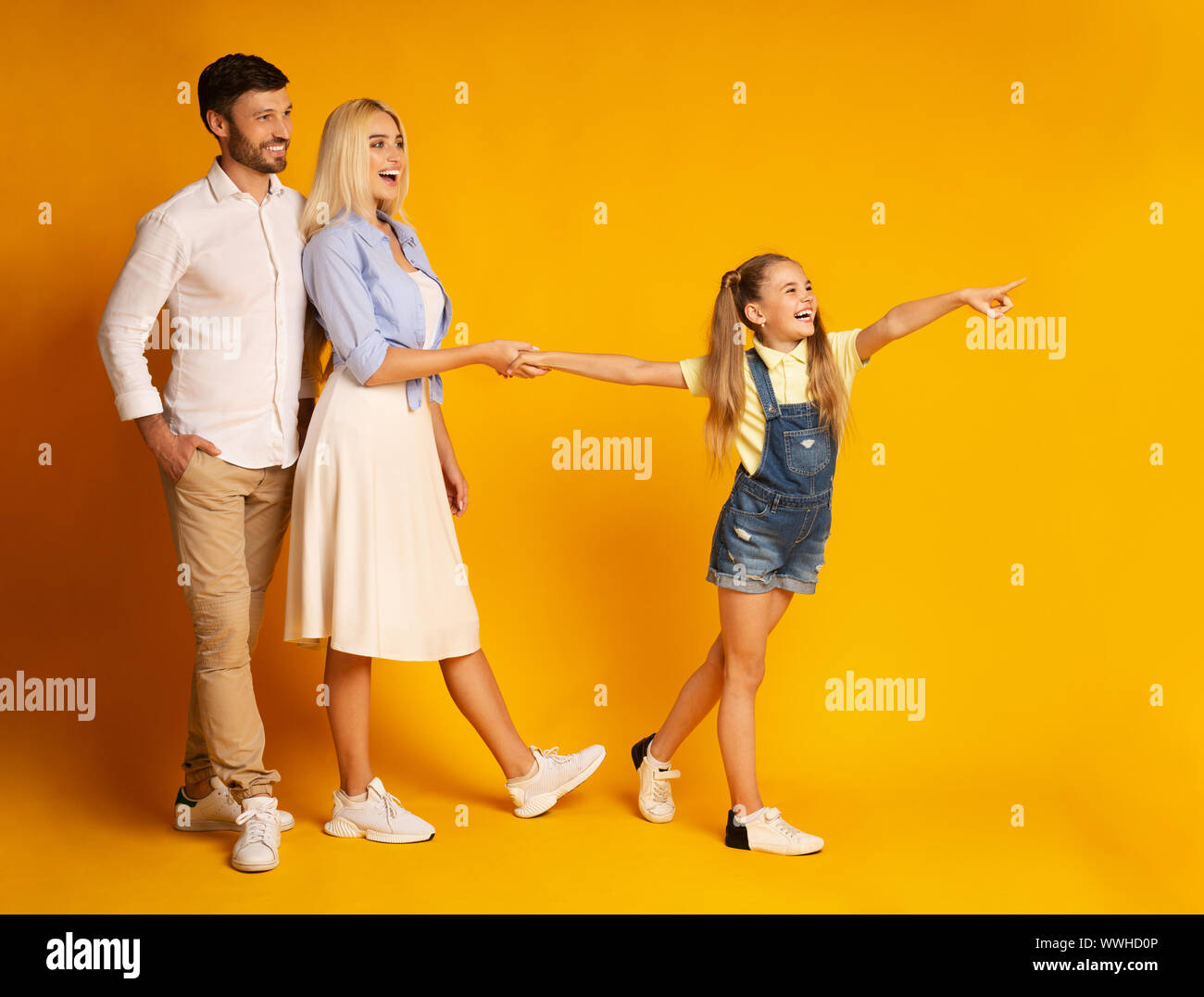 Daughter Pointing Finger Showing Something To Parents, Yellow Studio ...