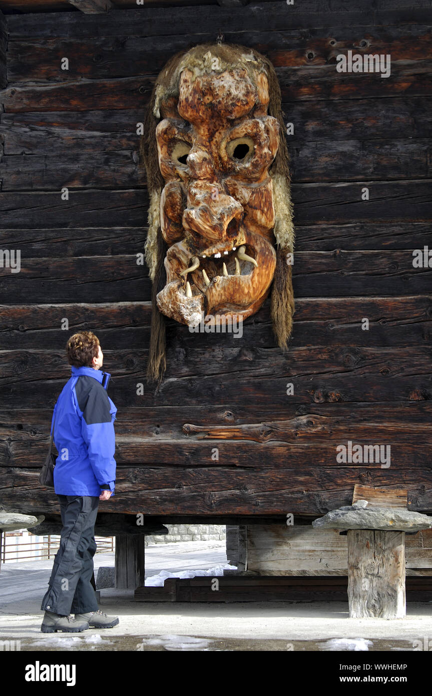 Woman looks at oversized traditional wooden mask made of pine wood ...