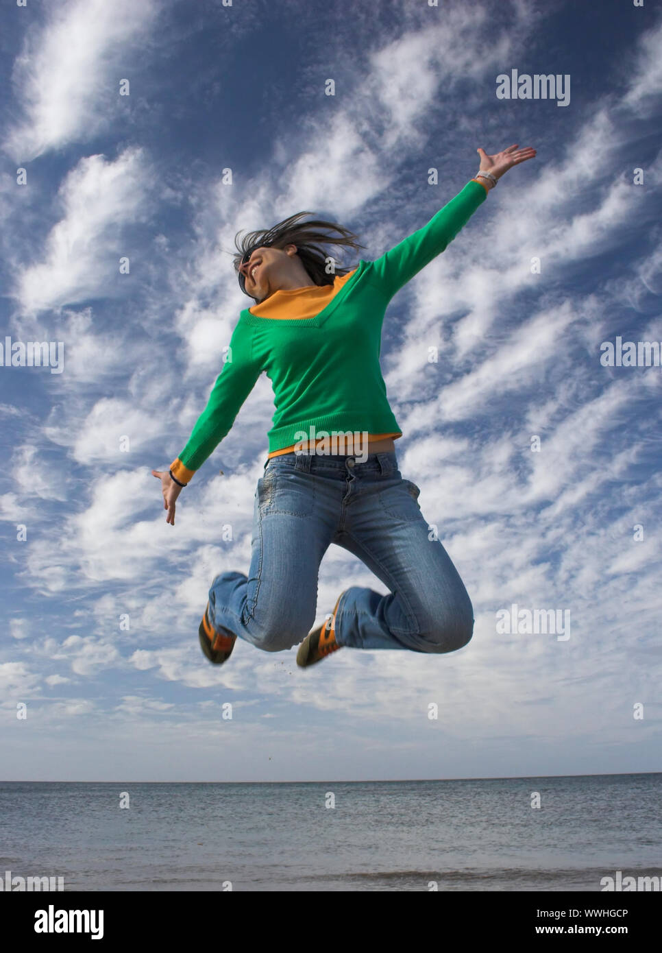 Young beautiful woman making a big jump on the beach Stock Photo - Alamy