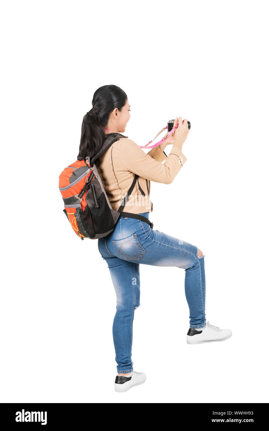 Rear view of Asian woman with a backpack holding a camera to take ...