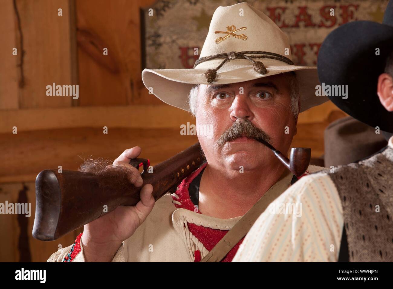 An old west fur trapper shoulders his rifle with a pipe in his mouth ...