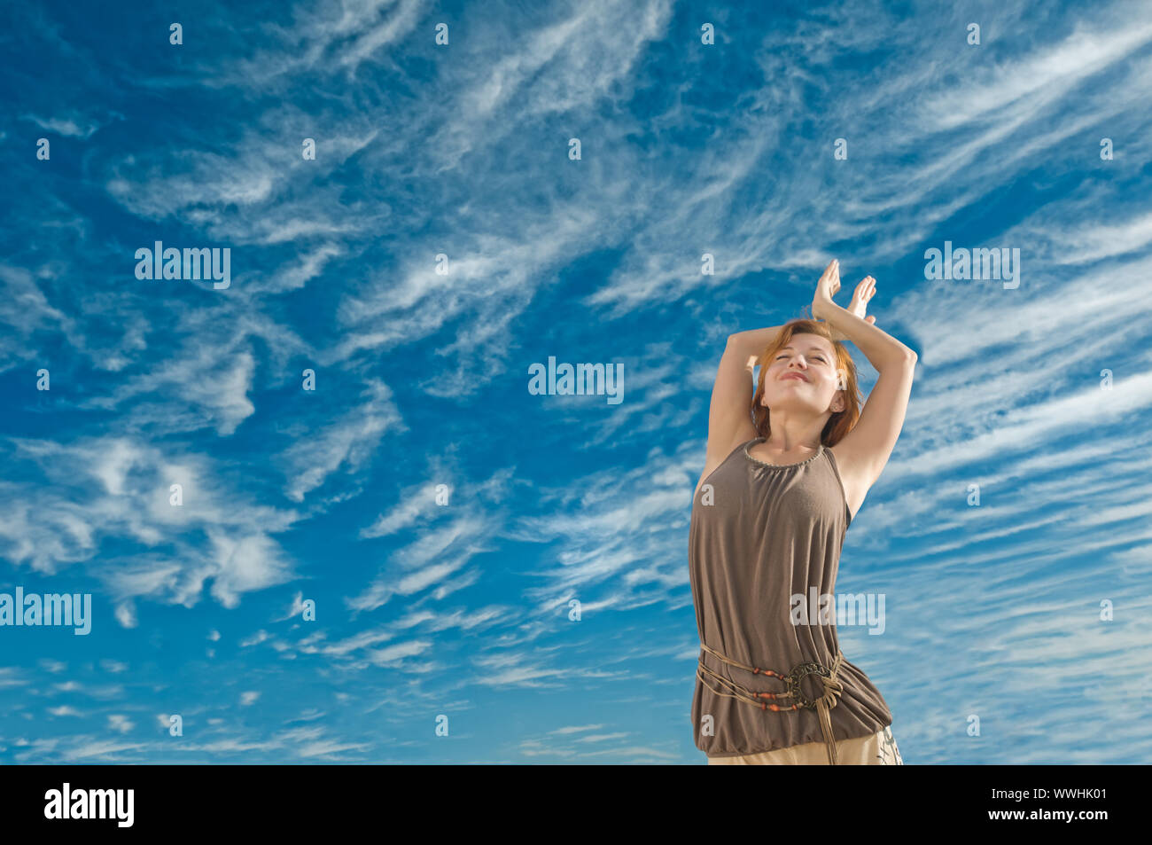 Beautiful young dancer performing yoga-dance outdoors with blue sky and ...