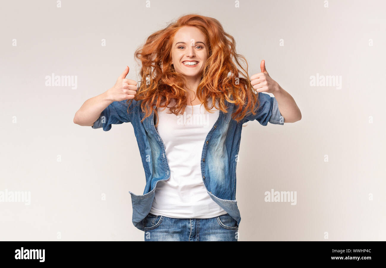 Happy ginger girl jumping and showing thumbs up Stock Photo - Alamy