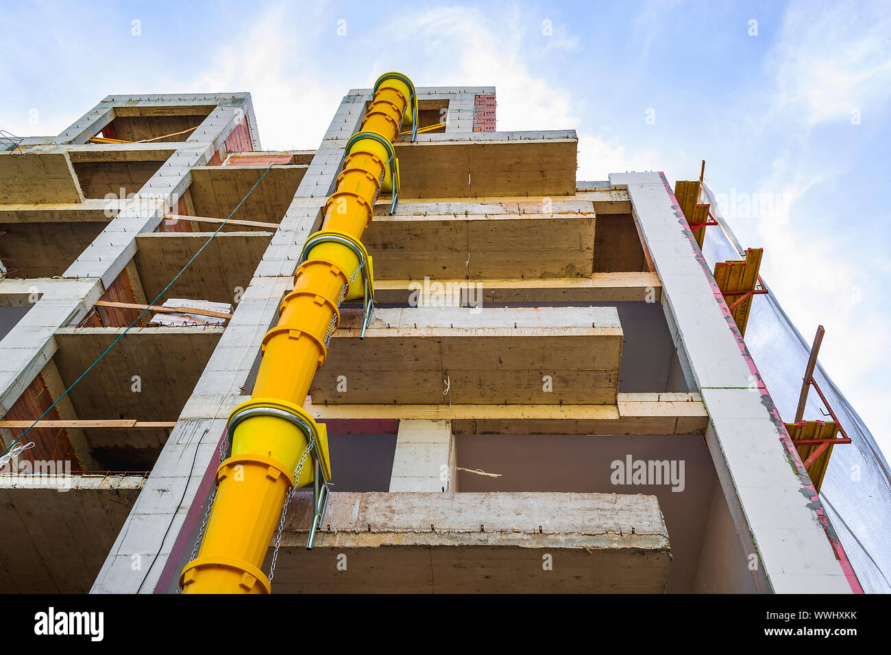 Suspended sections of yellow garbage chute on a facade of building ...