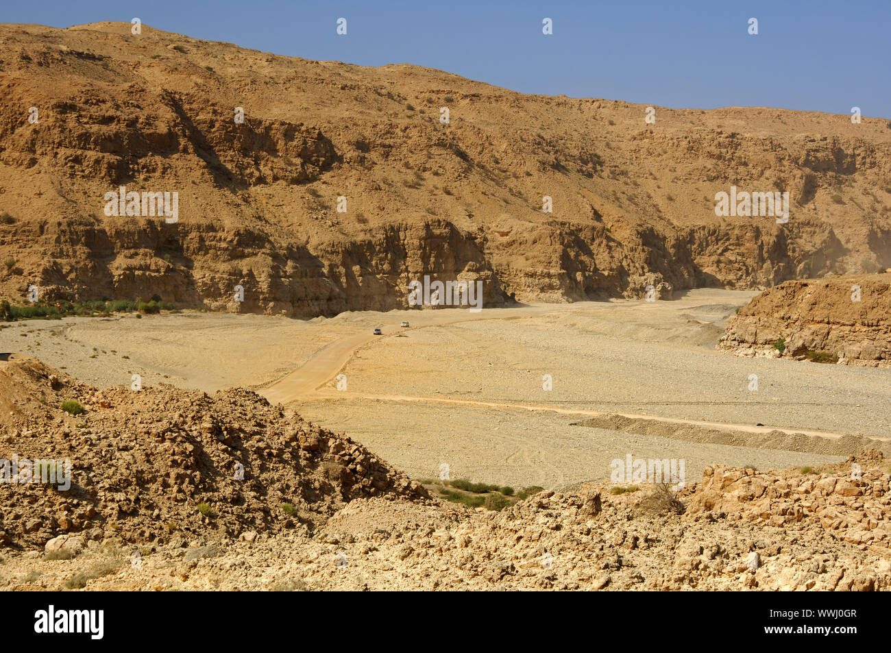 Vehicles on a dusty gravel road in a dry wadi in the north of the ...