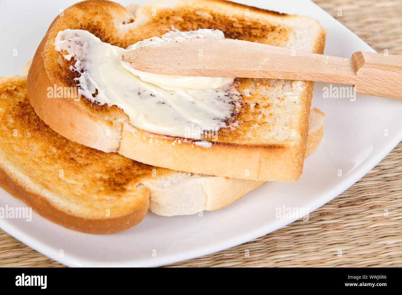Spreading toasts by wooden knife Stock Photo - Alamy