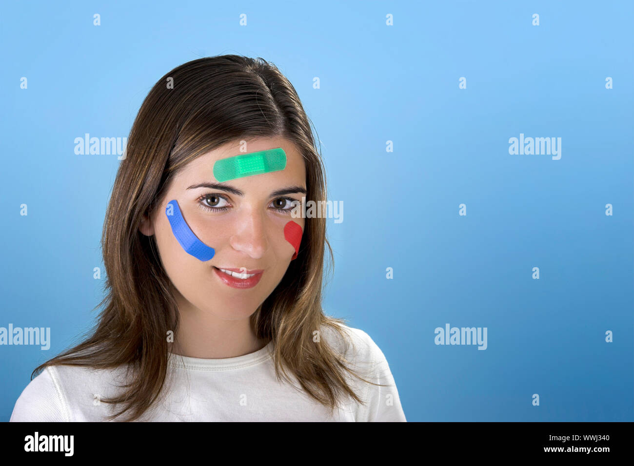 Beautiful woman with colored bandages on the face over a blue ...