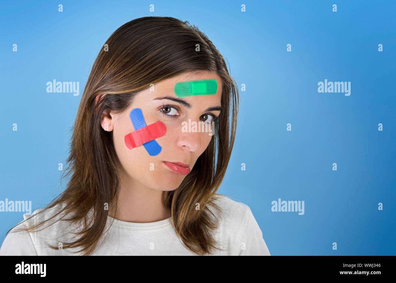 Beautiful woman with colored bandages on the face over a blue ...