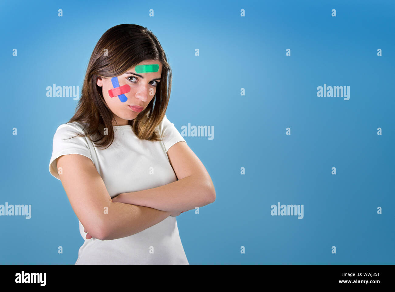 Beautiful woman with colored bandages on the face over a blue ...