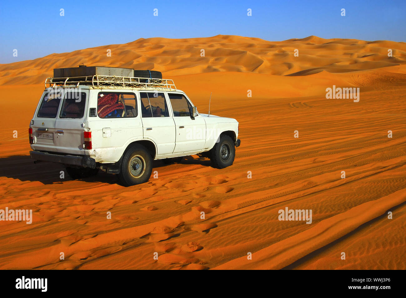 off-road vehicle on a desert road through sand dunes in the Sahara ...