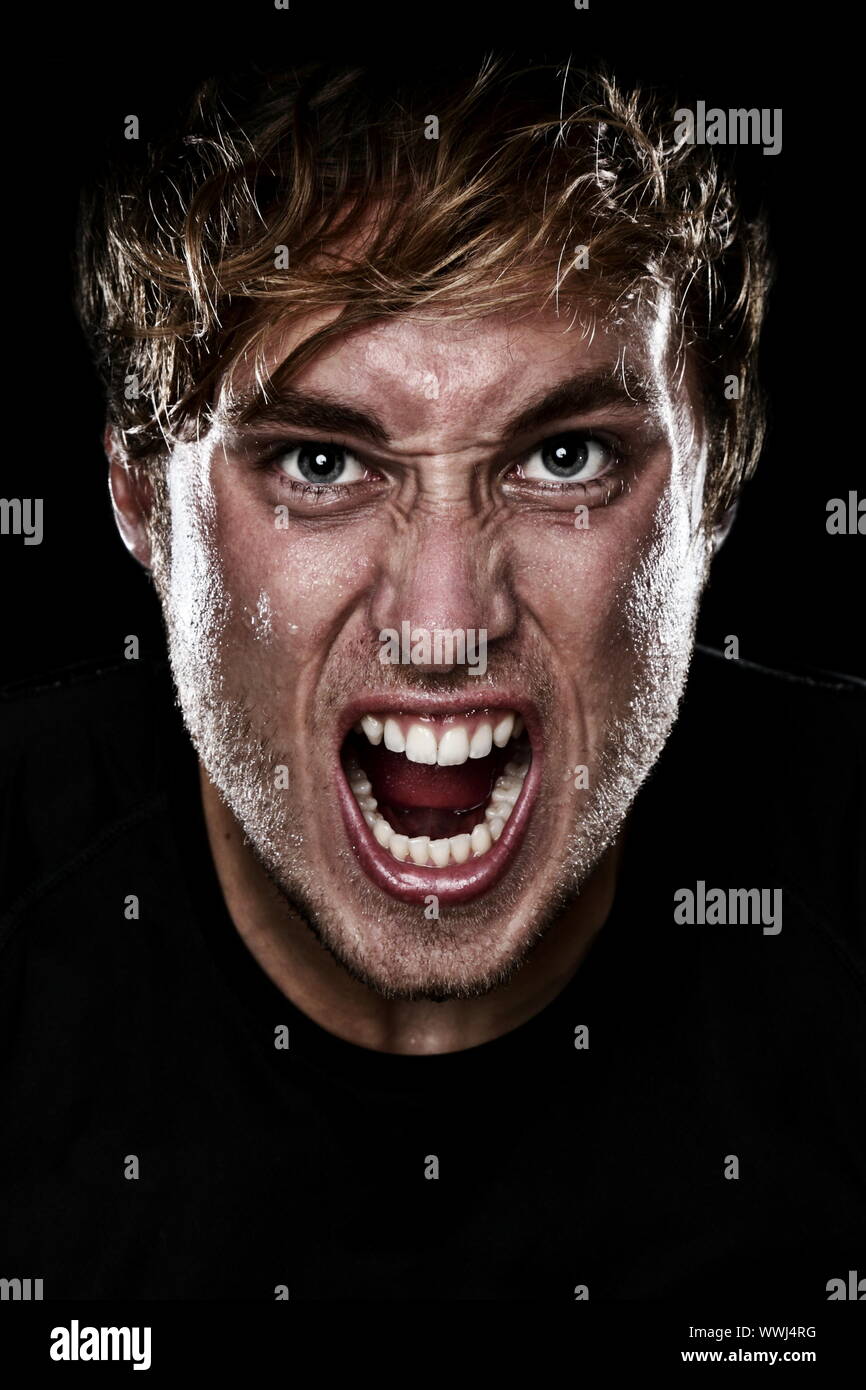 Man screaming angry aggressive at camera on black background. Young ...