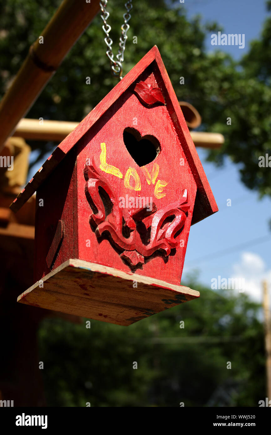Red birdhouse hanging in a community garden Stock Photo - Alamy
