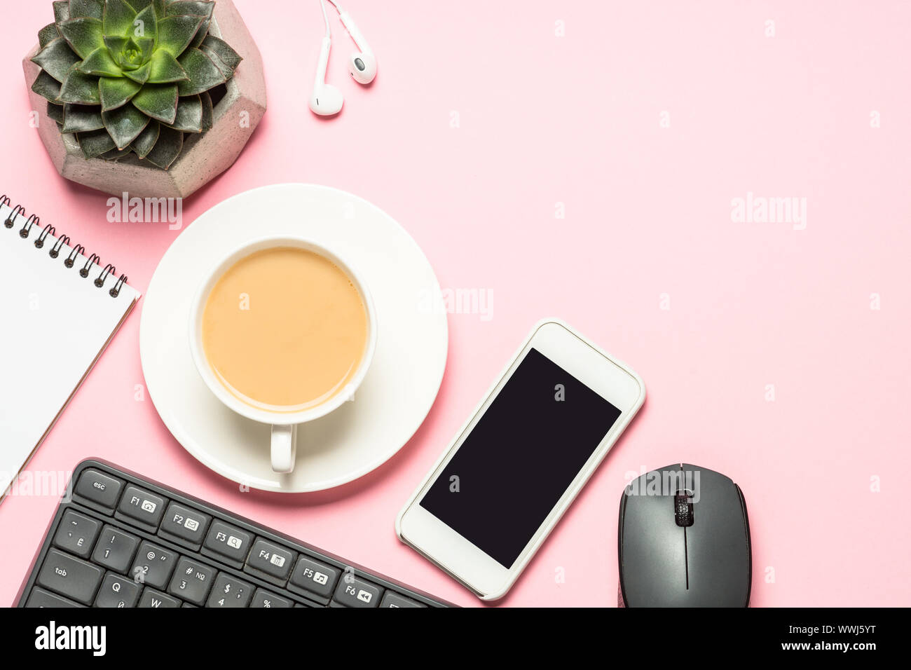 Office workplace with notepad, coffee cup and keyboard on pink ...