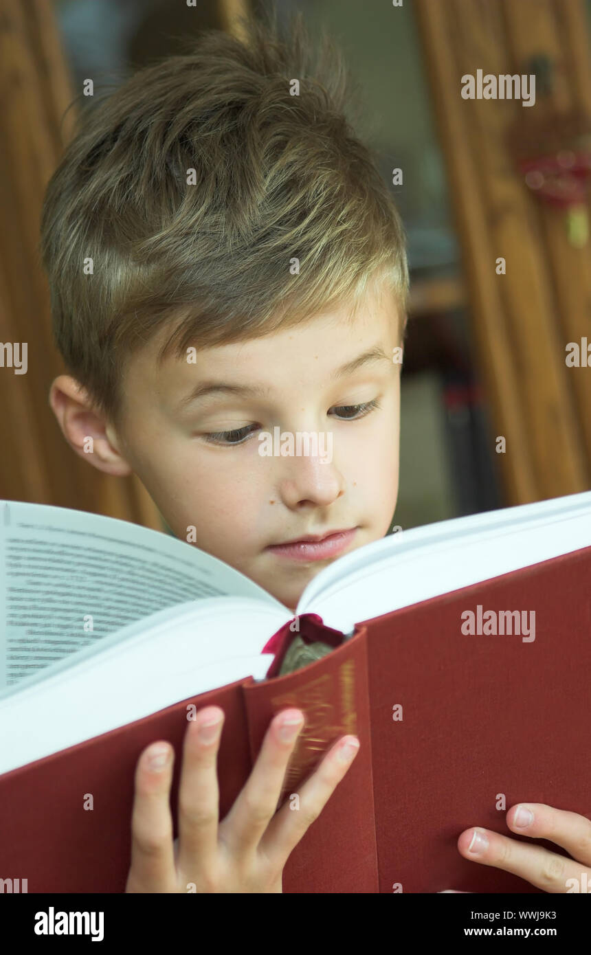 Young boy reading old, heavy book Stock Photo - Alamy