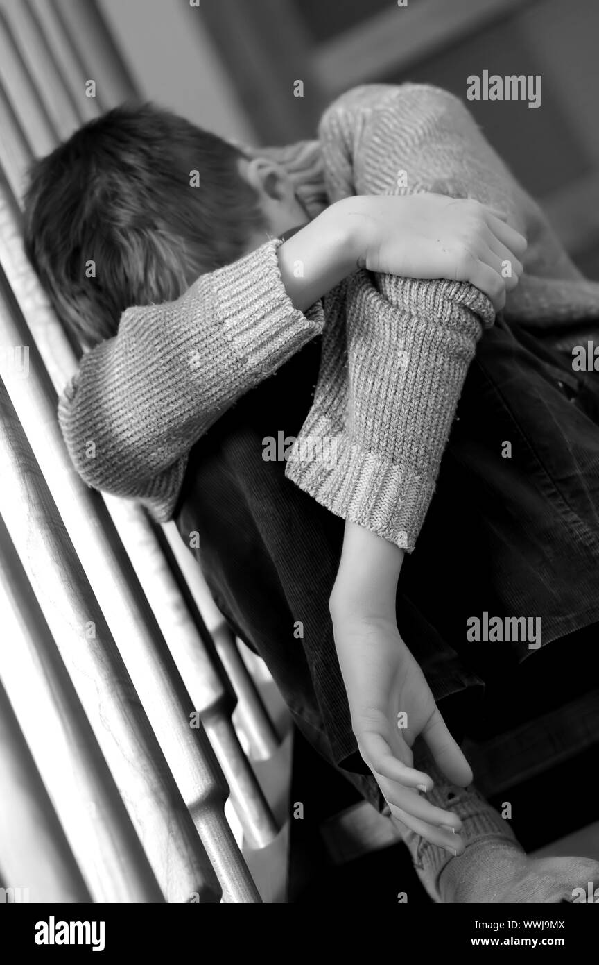 Portrait of young boy sitting sadly Stock Photo - Alamy