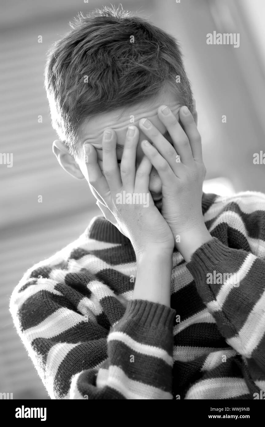 Portrait of young boy sitting sadly Stock Photo - Alamy