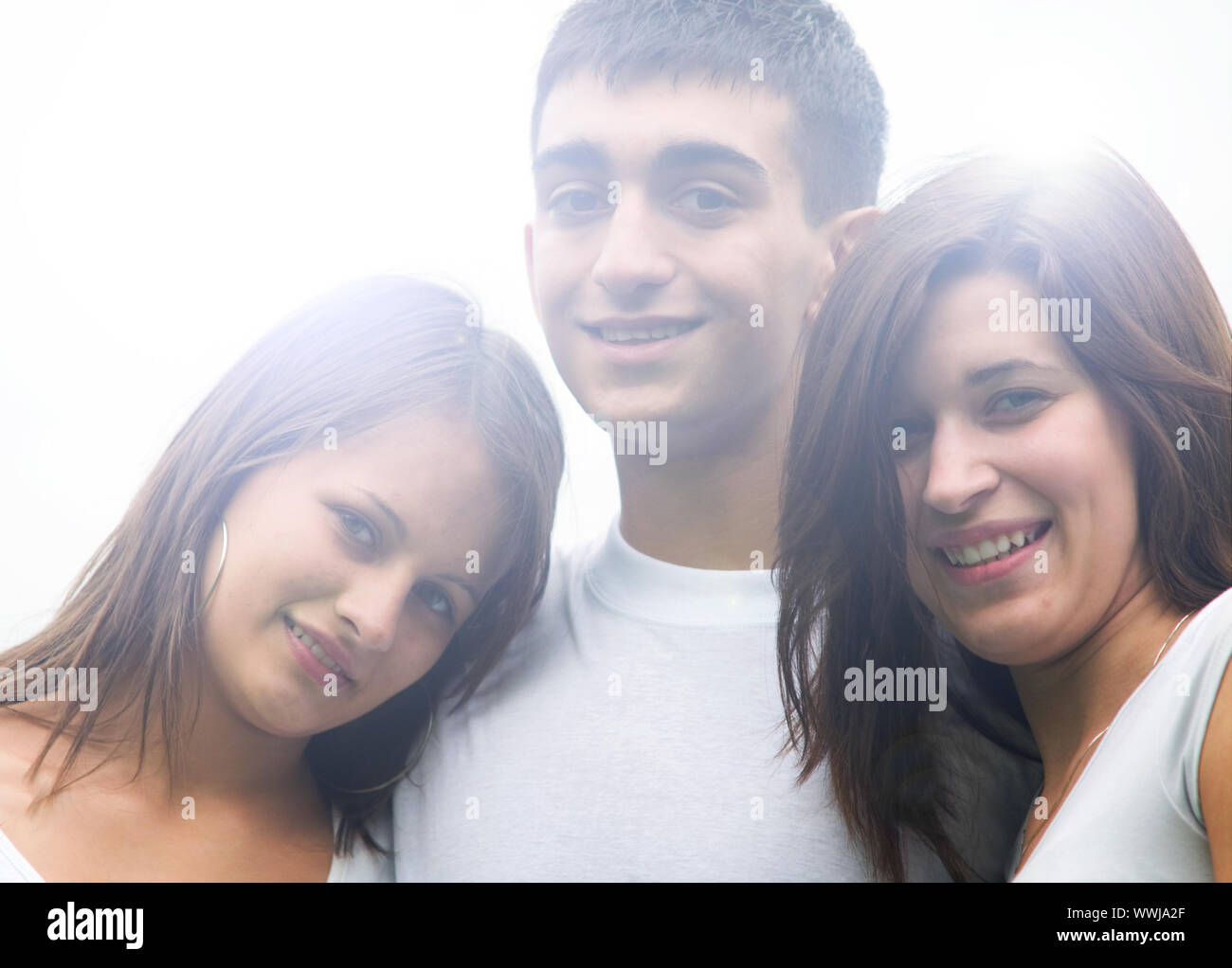 Low contrast shot of three young happy friends standing together and ...