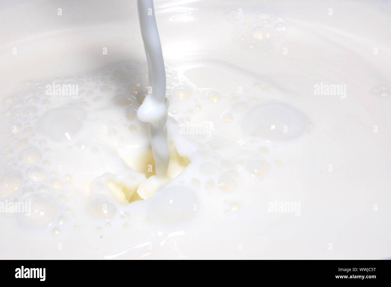 milk splashing into fresh milk with drops Stock Photo - Alamy