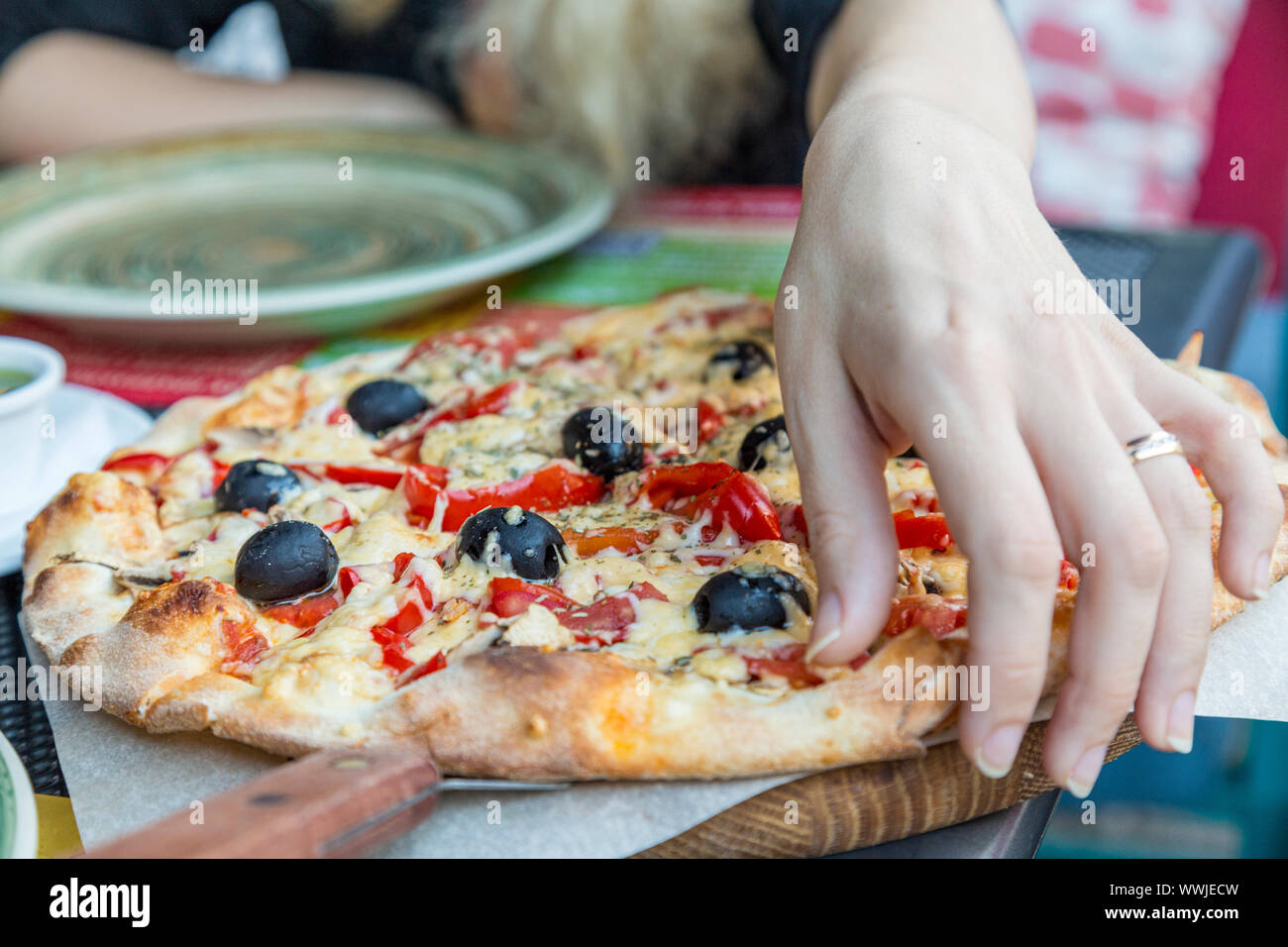 Woman hand picking up a slice of pizza Stock Photo - Alamy