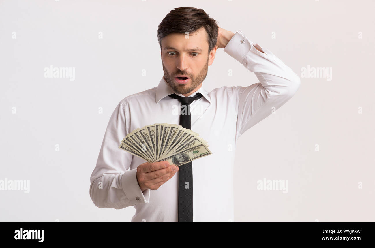Shocked man holding money scratching his head, studio shot Stock Photo ...