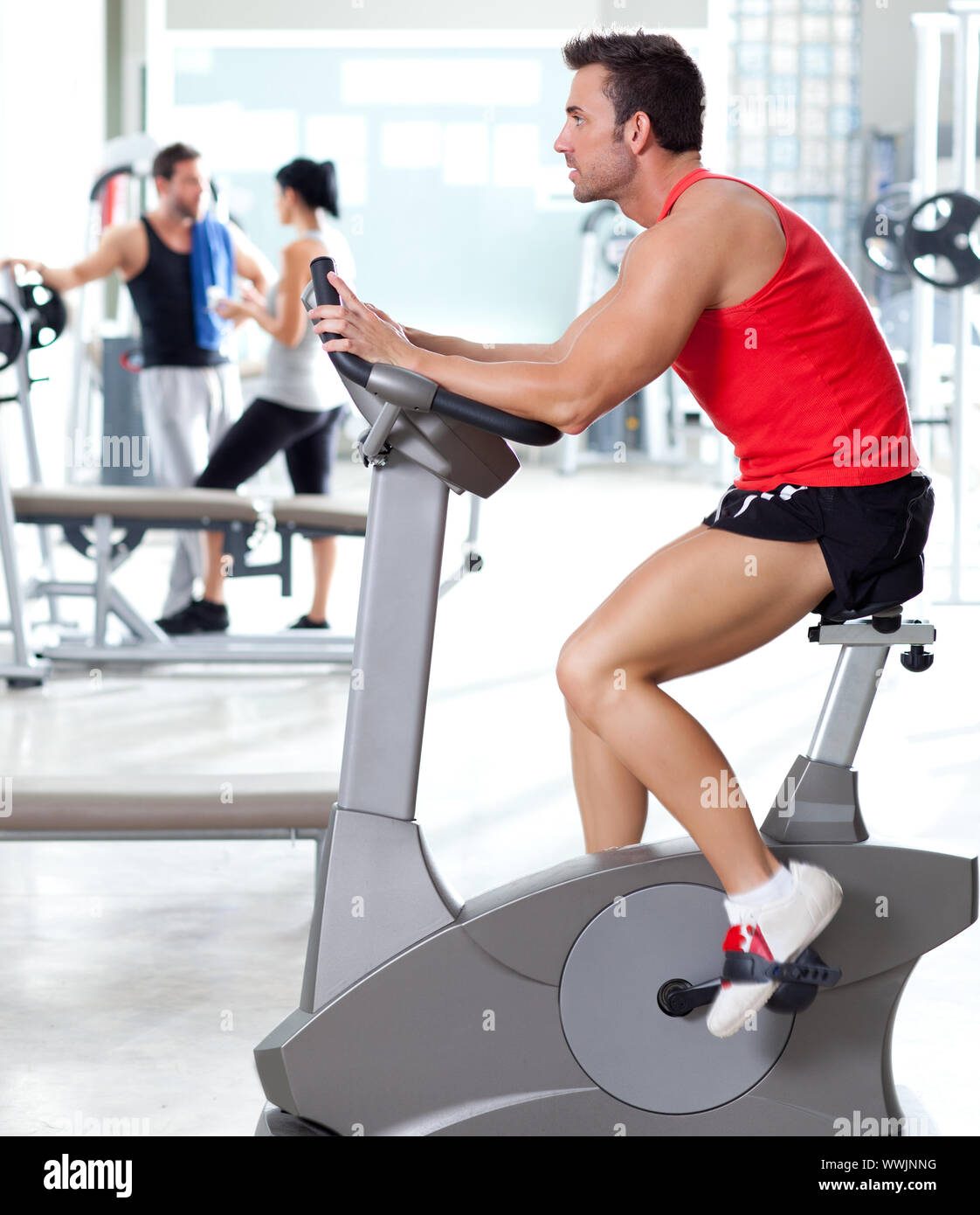man on stationary bicycle at sport fitness gym interior Stock Photo - Alamy