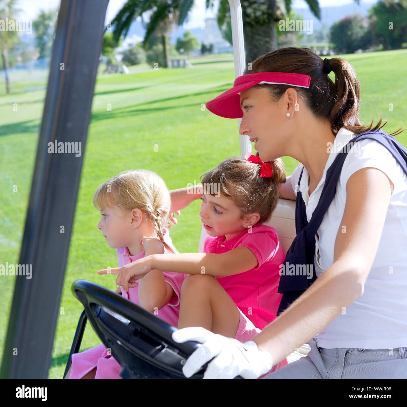 golf course family mother and daughters in buggy green grass field ...
