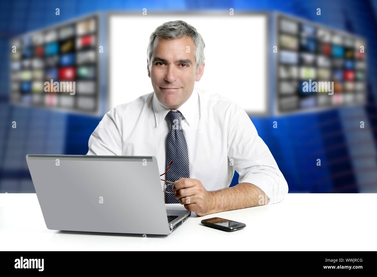 gray hair tv news screen presenter laptop smiling white desk Stock ...
