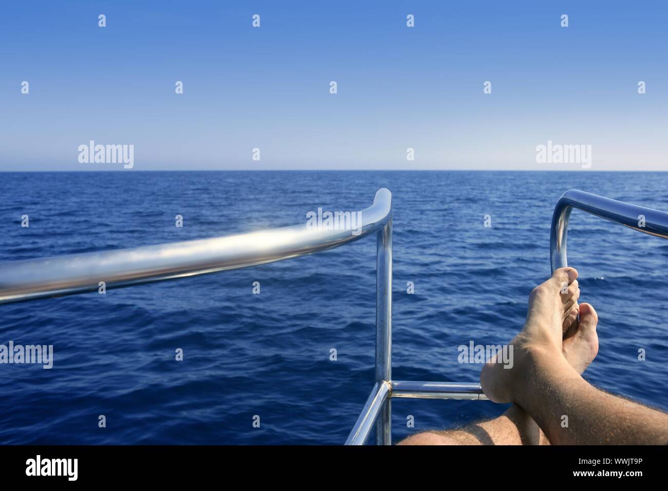 Boat bow summer vacation with male man feet relaxed over blue ocean sea ...