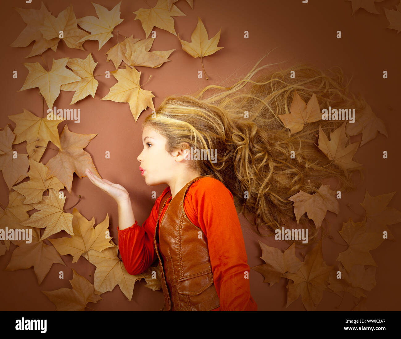 autumn fall little blond girl on dried tree leaves blowing wind with ...