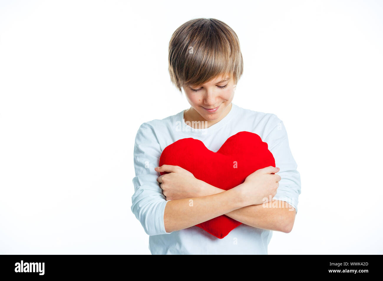 A cute young boy in love with a red plush heart in his hands. isolated ...