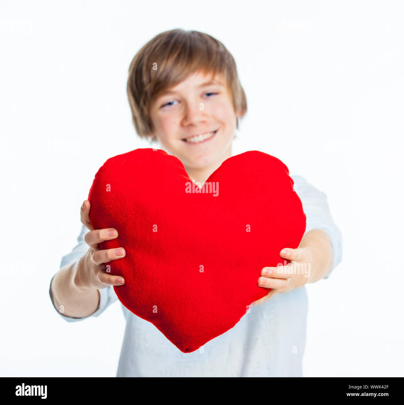 A cute young boy in love with a red plush heart in his hands. Focus on ...