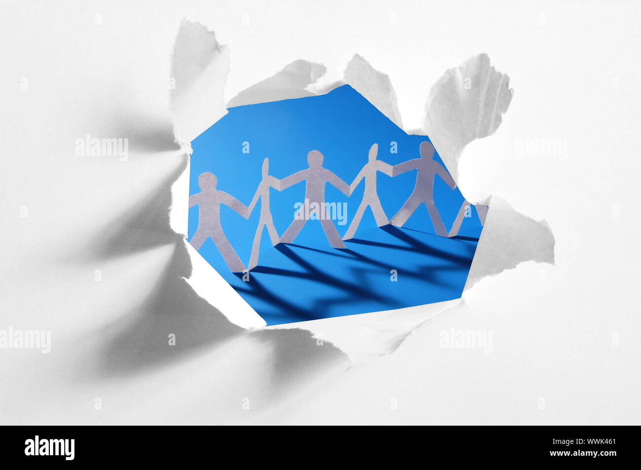 chain of paper man in a hole showing teamwork Stock Photo - Alamy