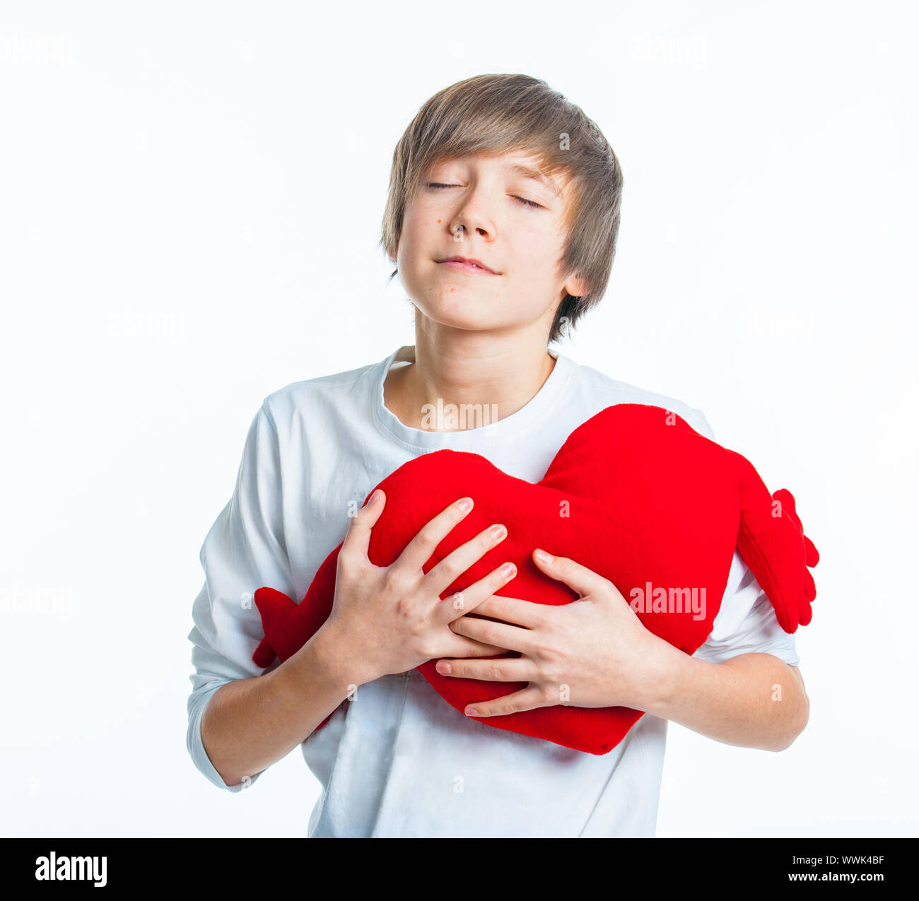 A cute young boy in love with a red plush heart in his hands. isolated ...