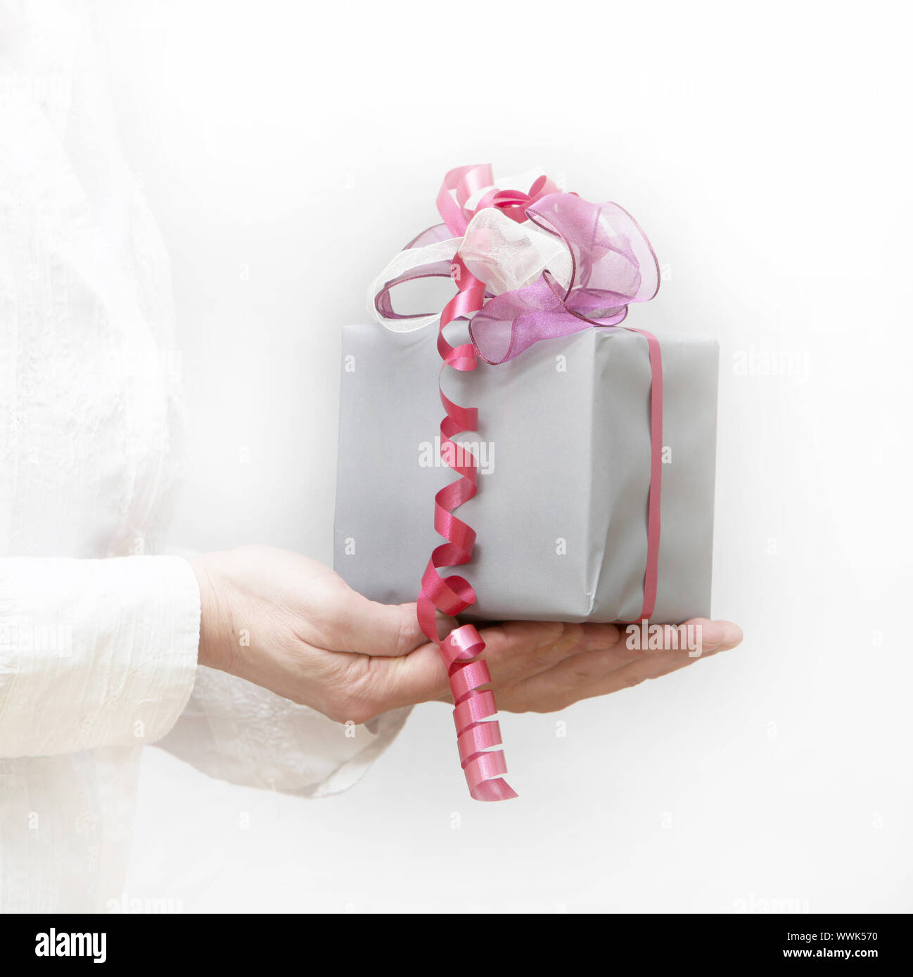 Woman presented with a gift ribbon - white background Stock Photo - Alamy