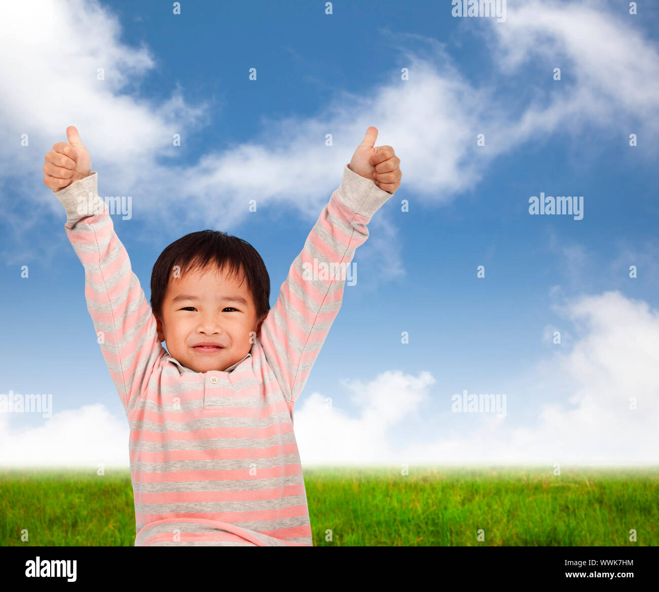 Smiling kid with thumbs up and standing on the green meadow Stock Photo ...