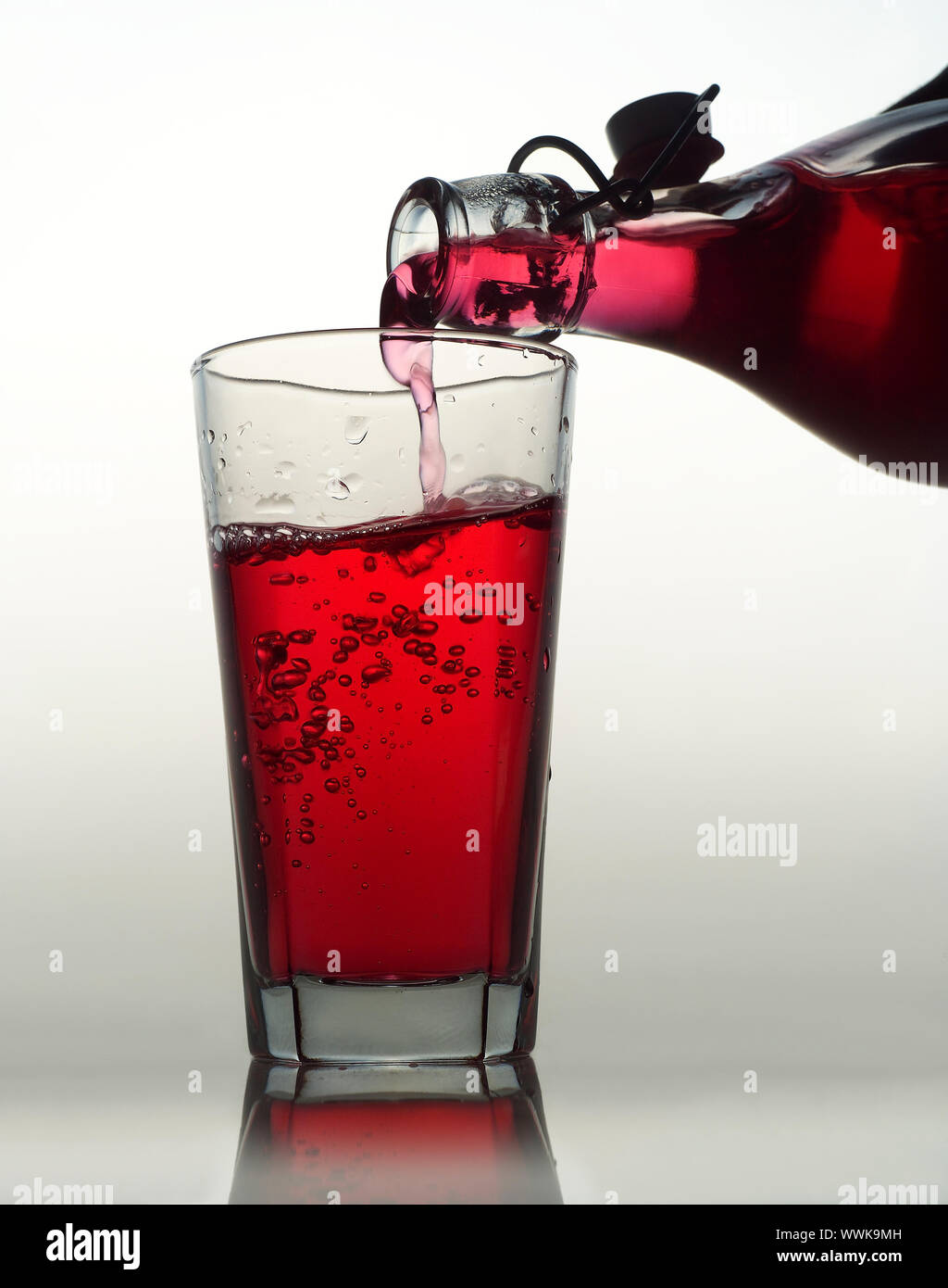 Pouring Red Lemonade in a glass on white background Stock Photo - Alamy