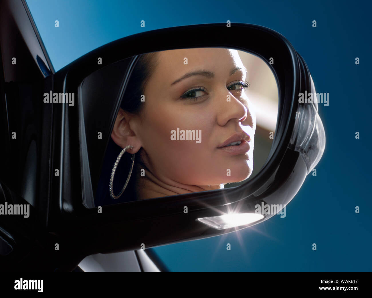 Young woman sits on driver's seat and Looks in the rear-view mirror ...