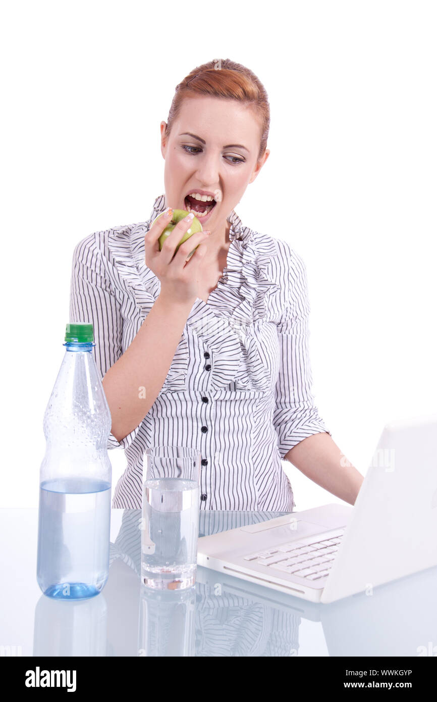 Young woman with laptop and snack at desk Stock Photo - Alamy
