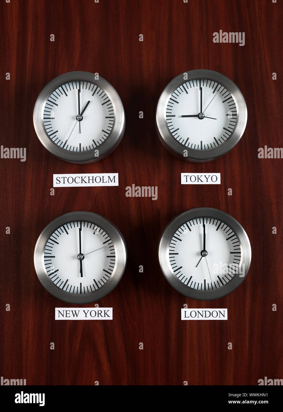Four clocks with different time on Teak background Stock Photo - Alamy